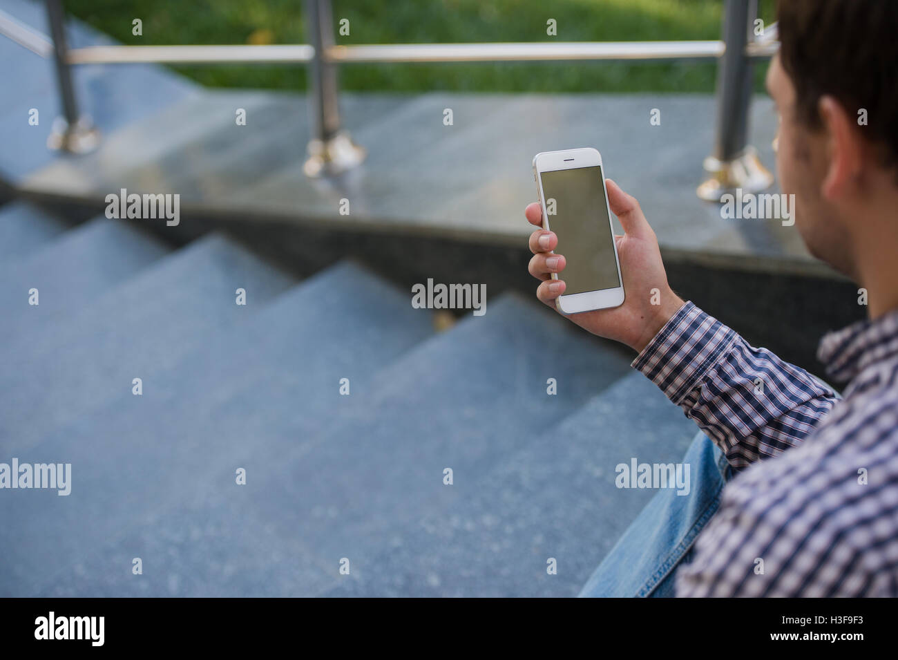 Man uses his Mobile smart Phone outdoor while sitting on a stairs ...
