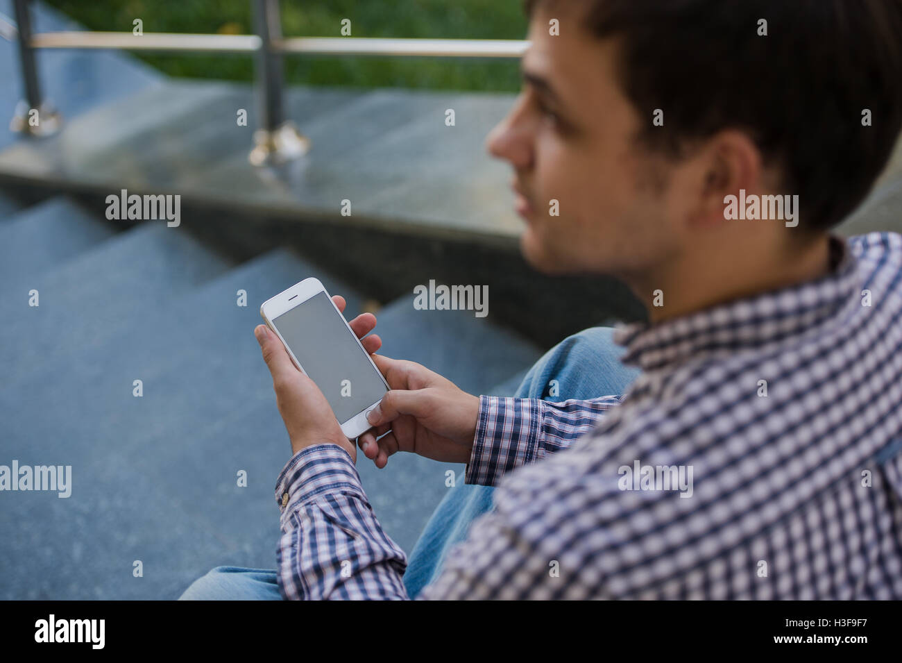 Man uses his Mobile smart Phone outdoor while sitting on a stairs ...