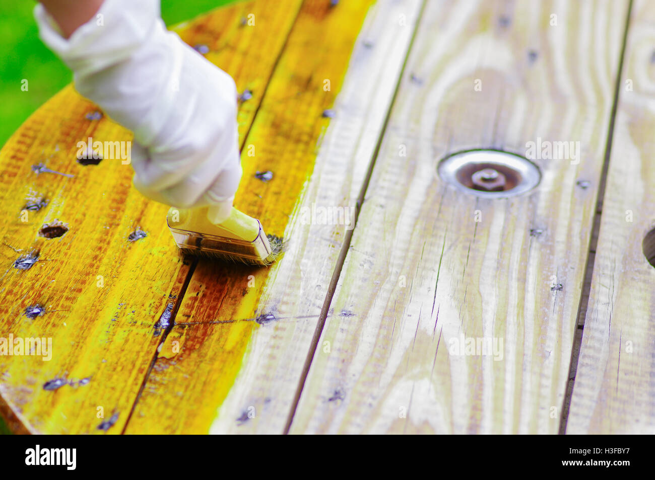 hand with a glove holding a brush and applying a protective lacquer to ...