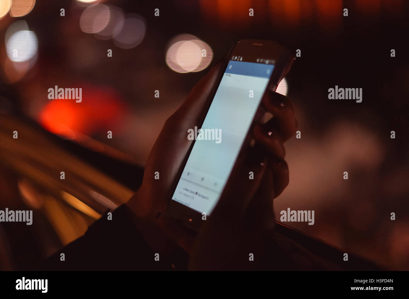 Girl using smart phone at night in front of blurred city lights Stock ...