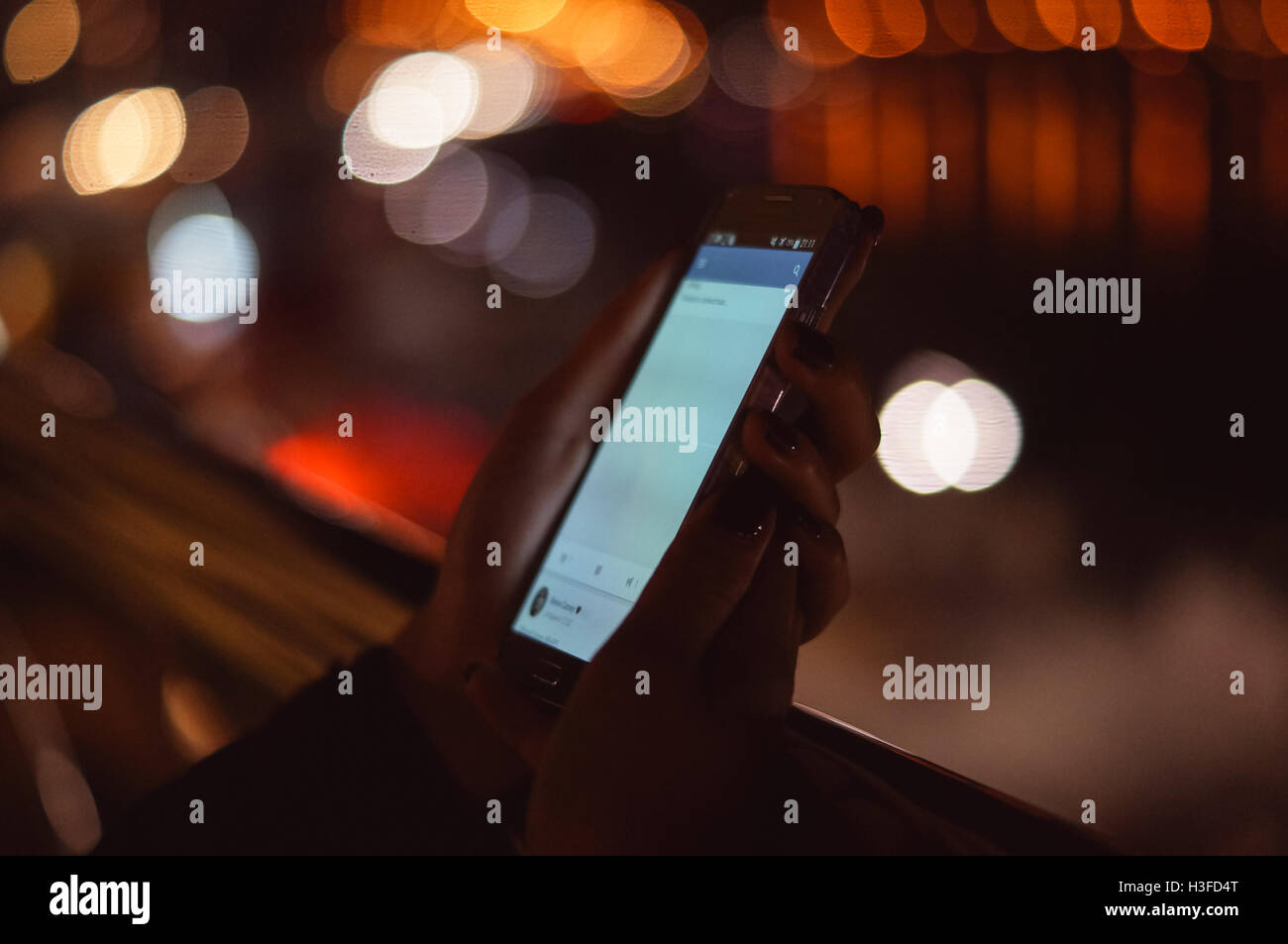 Girl using smart phone at night in front of blurred city lights Stock ...