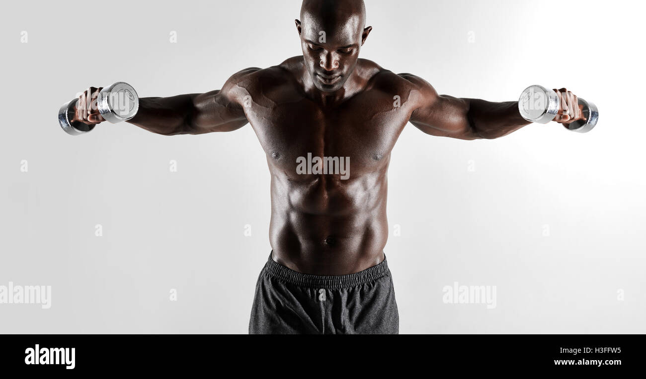 Studio shot of a male model exercising with dumbbells in both hands on ...