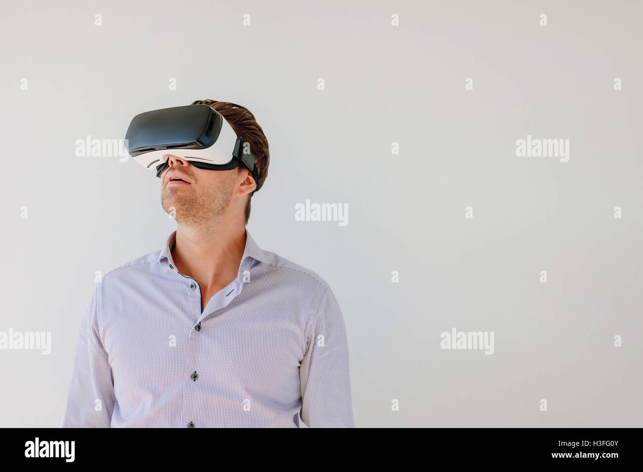 Shot of young man in VR headset looking away at the objects in virtual ...