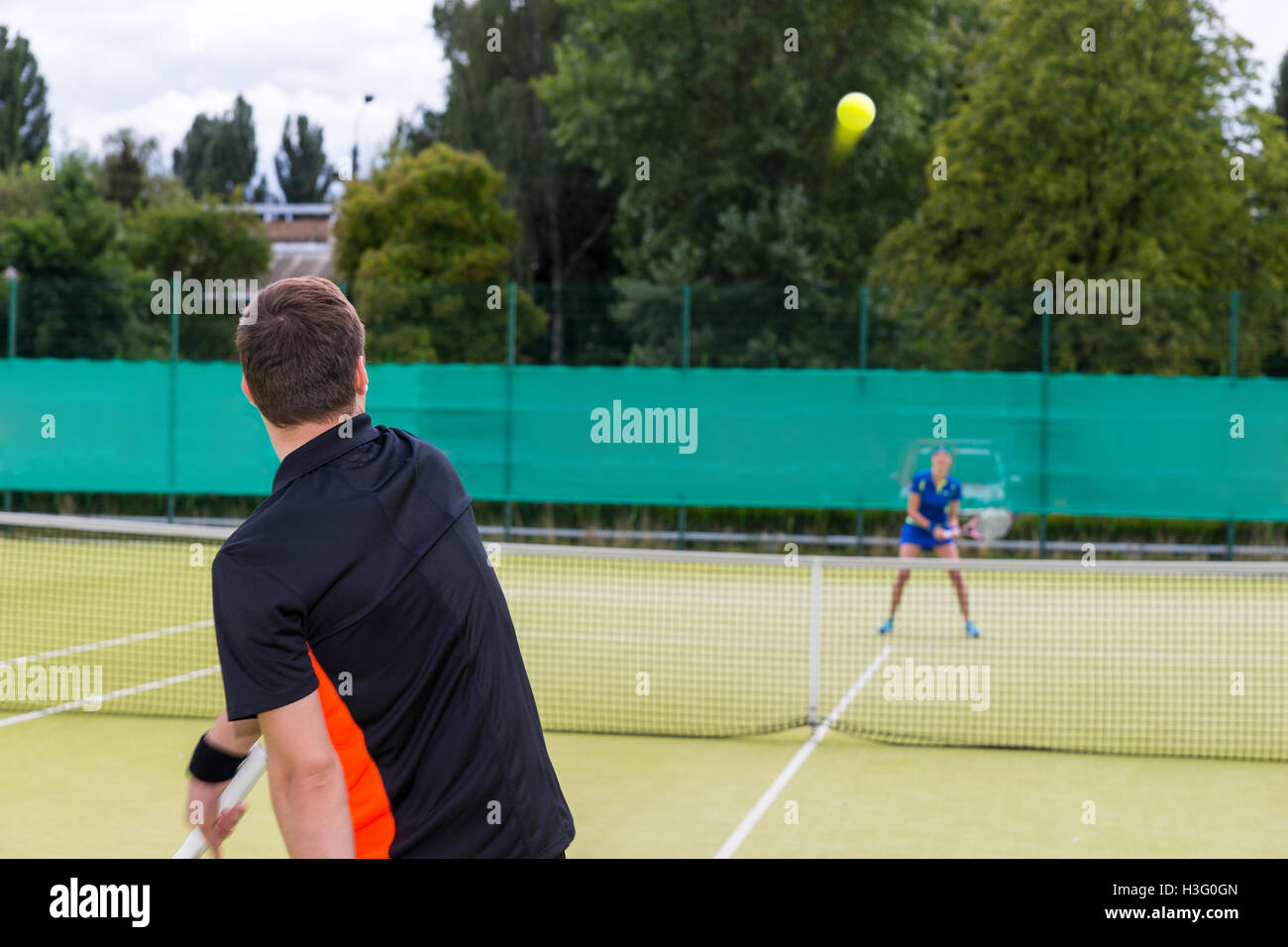 View from the back on a male tennis player wearing a sportswear serving ...