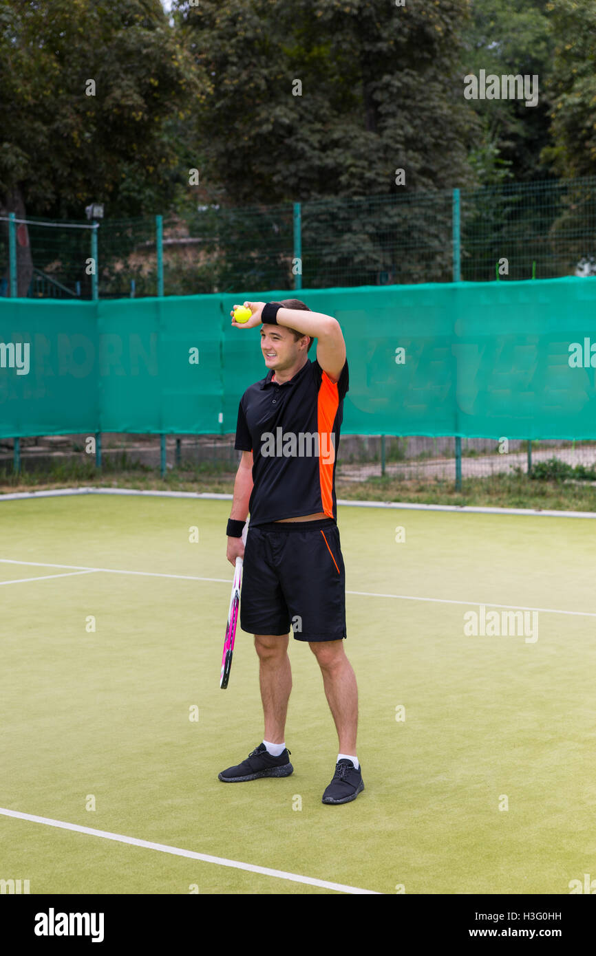 Tired male tennis player wearing a sportswear holding tennis ball and ...