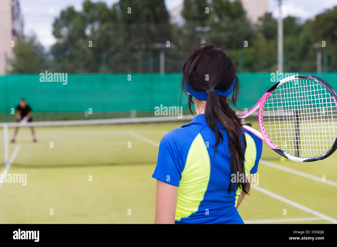 Backside view of a girl with tennis racket on her shoulder in sports ...