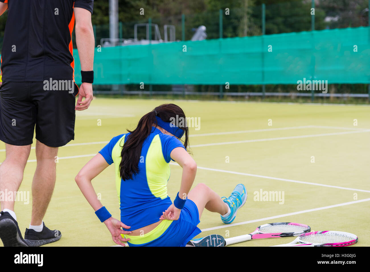 Female tennis player is sitting on the court and her male tennis ...