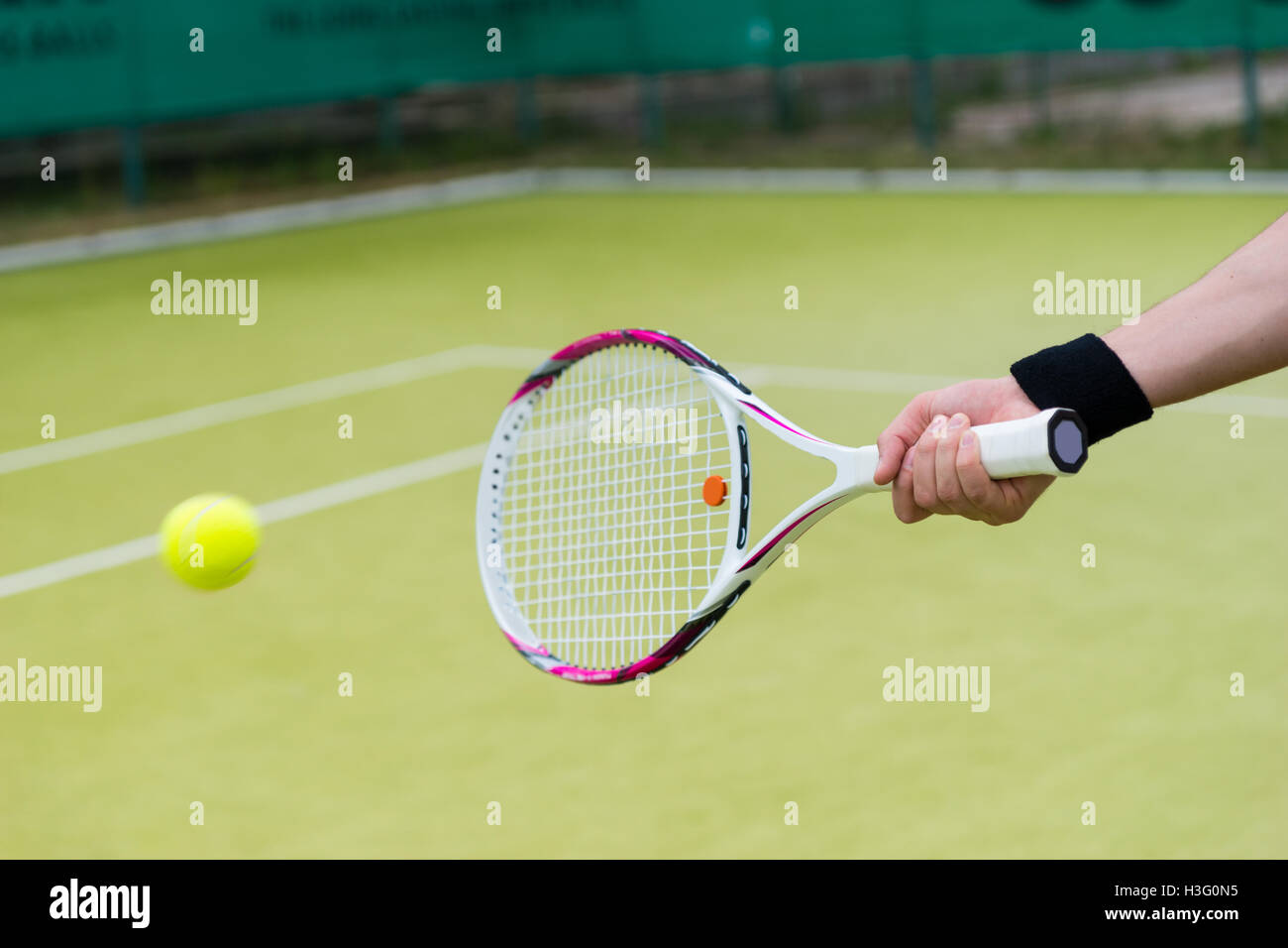 New pink racket and ball in action at green tennis court Stock Photo ...