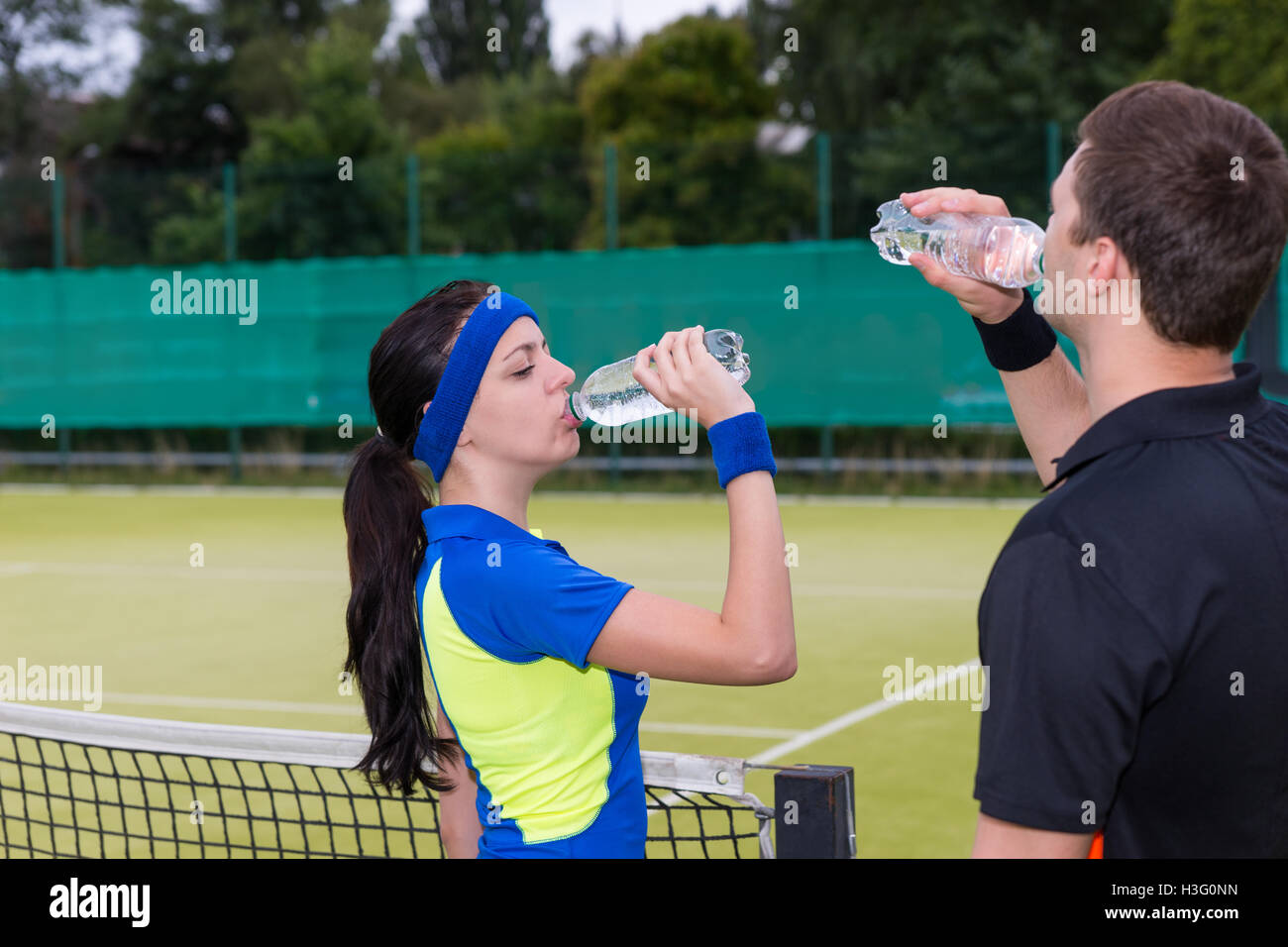 Couple of tennis players wearing a sportswear drinking water after ...