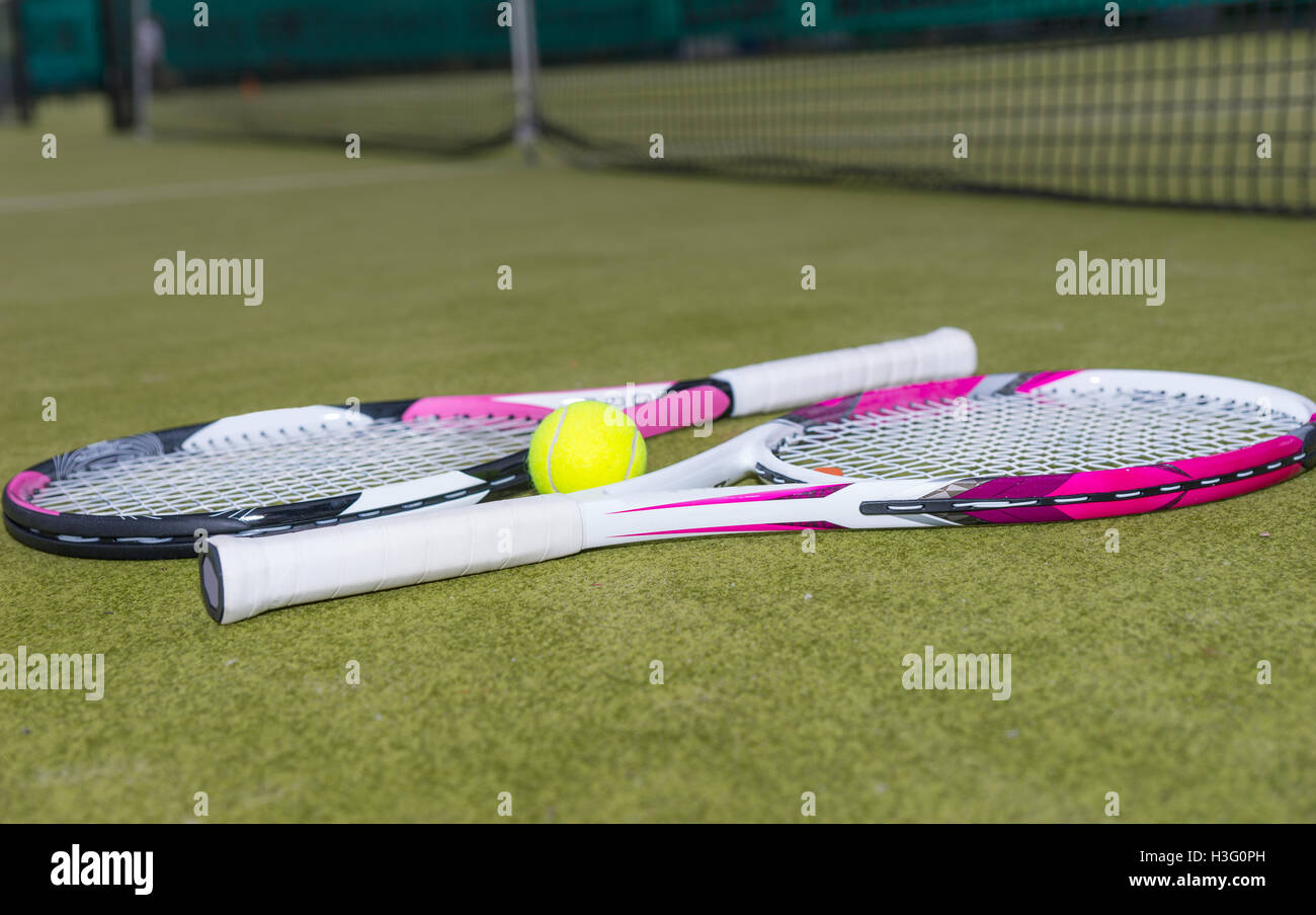Side view on tennis rackets with a tennis ball on a green grass court ...