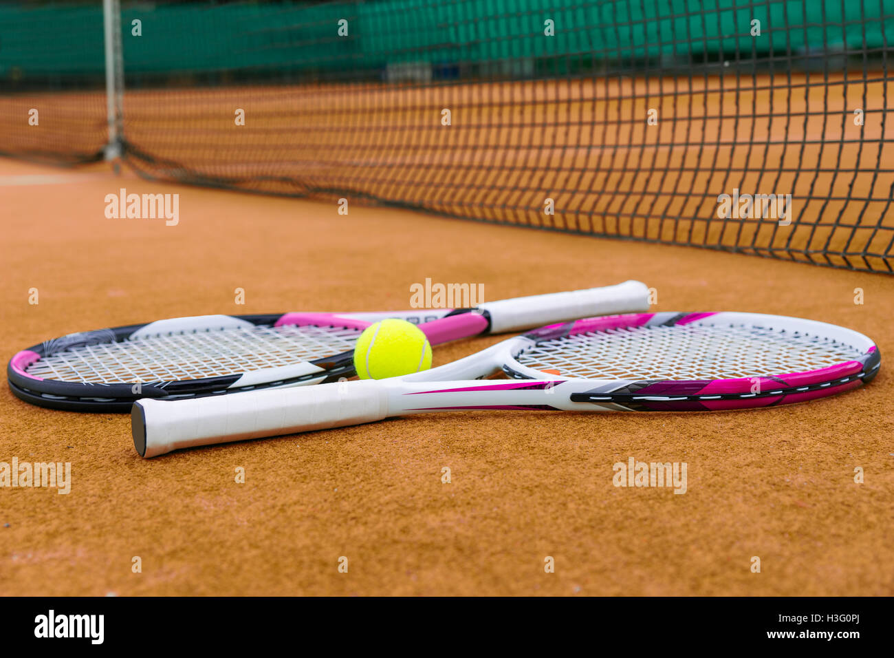 Side view on tennis rackets with a tennis ball on clay court outdoors ...