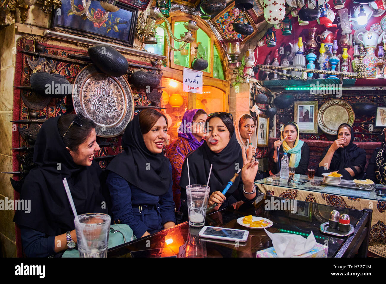 Iran, Isfahan, Azadegan teahouse, young women smoking a water pipe ...