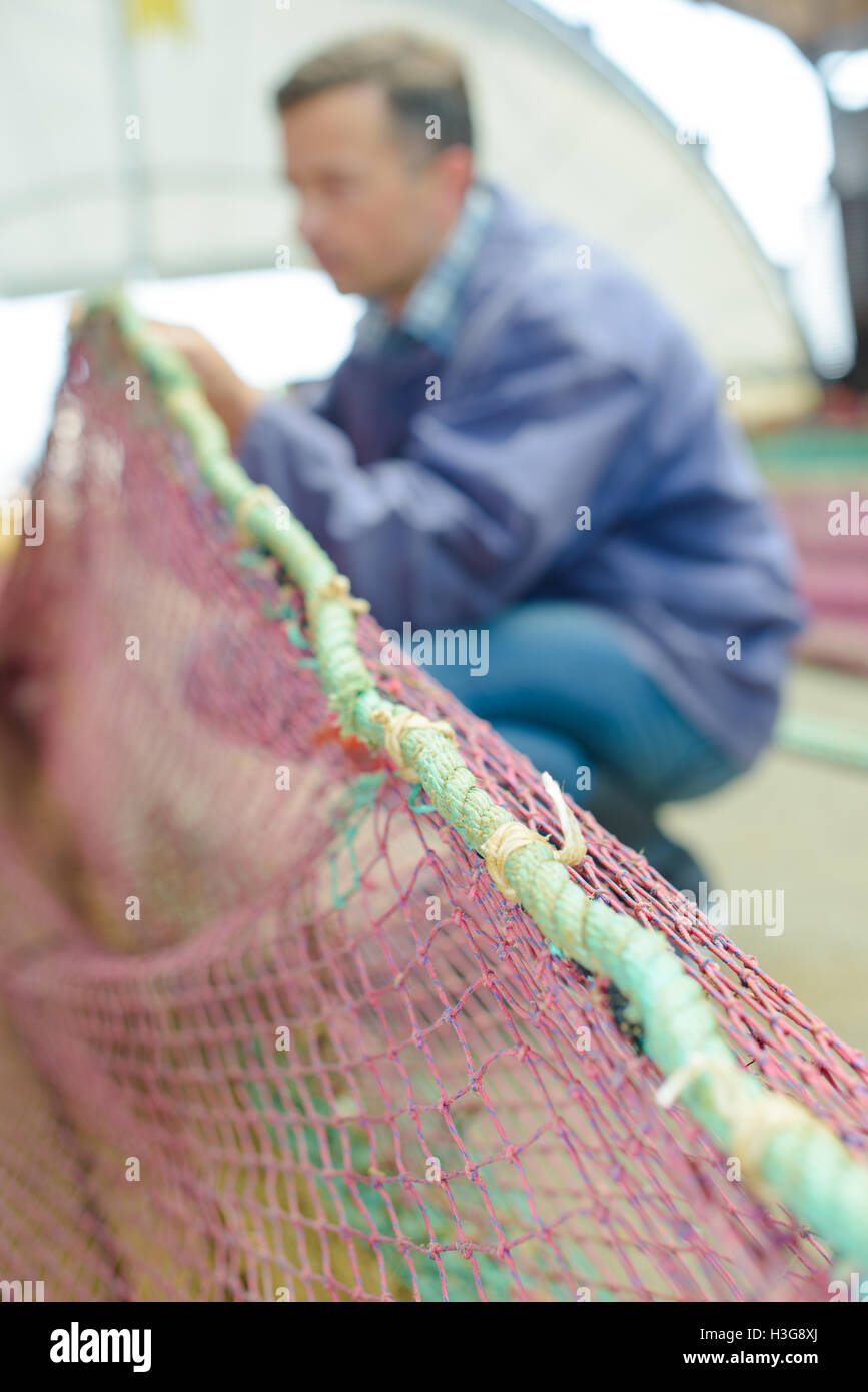 Man working on fishing net Stock Photo - Alamy