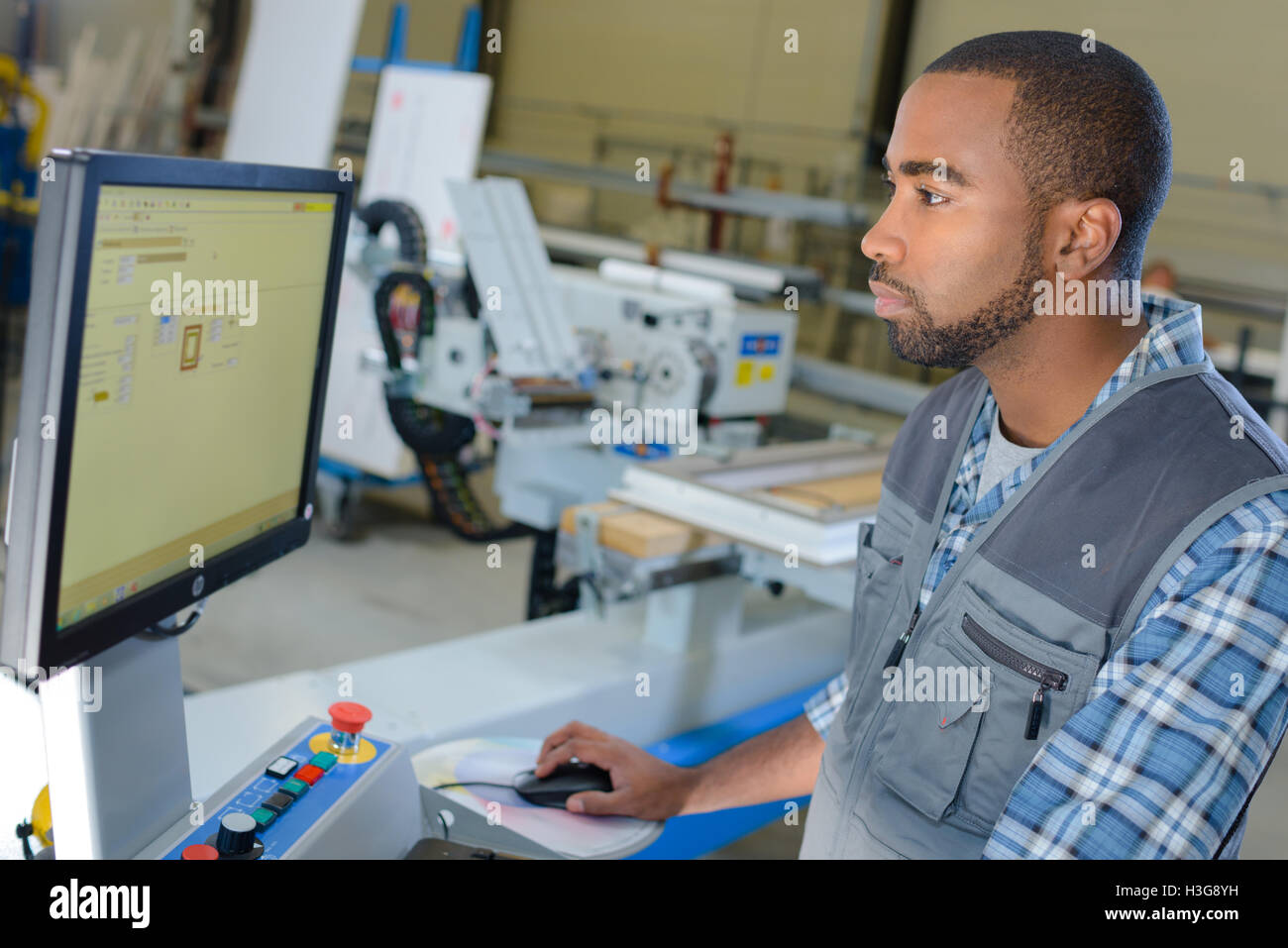 Man operating computer in industrial setting Stock Photo - Alamy