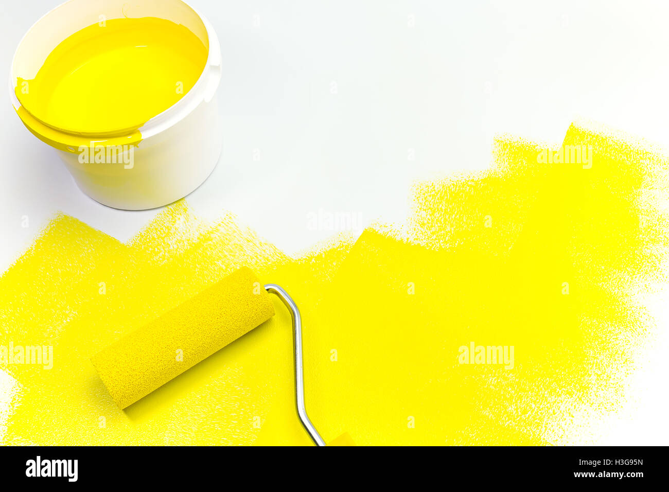 can of yellow paint and paint roller on white background Stock Photo ...