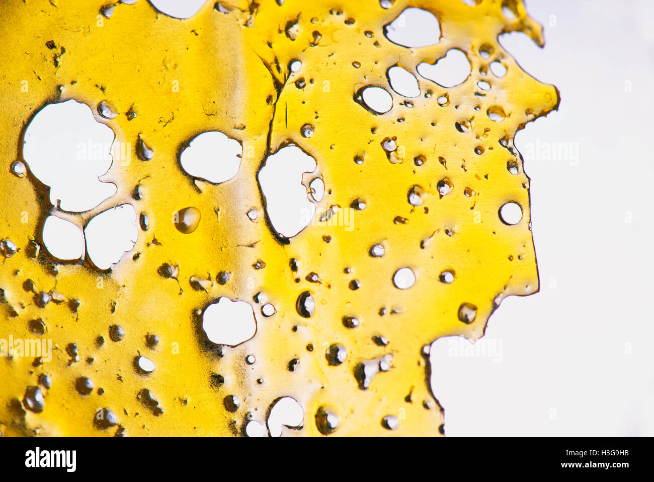 A piece of cannabis oil concentrate aka shatter isolated against white ...