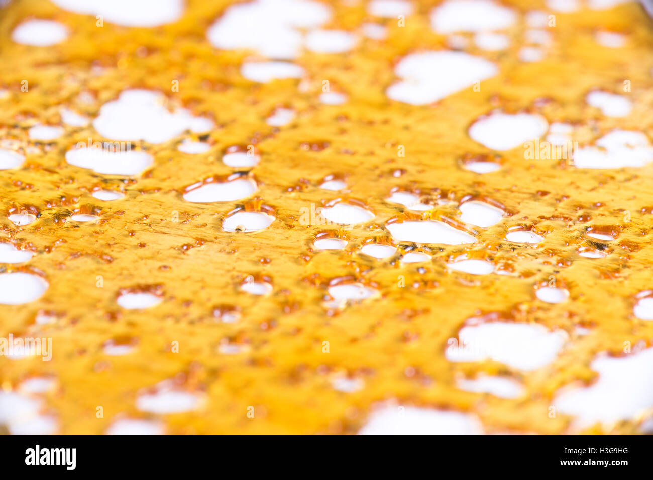 A piece of cannabis oil concentrate aka shatter isolated against white ...