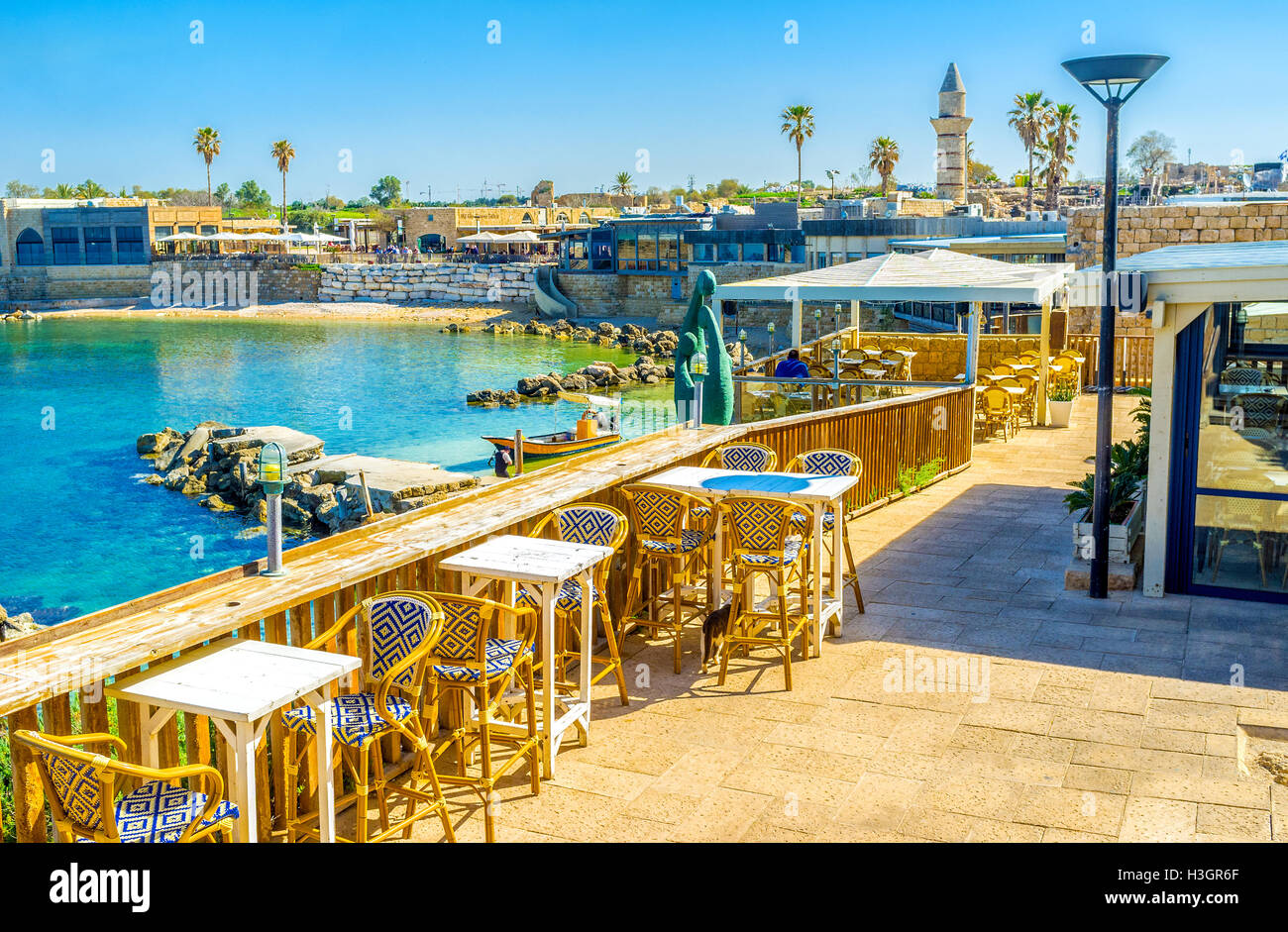 The outdoor restaurant in harbor of Caesarea overlooks the buildings ...