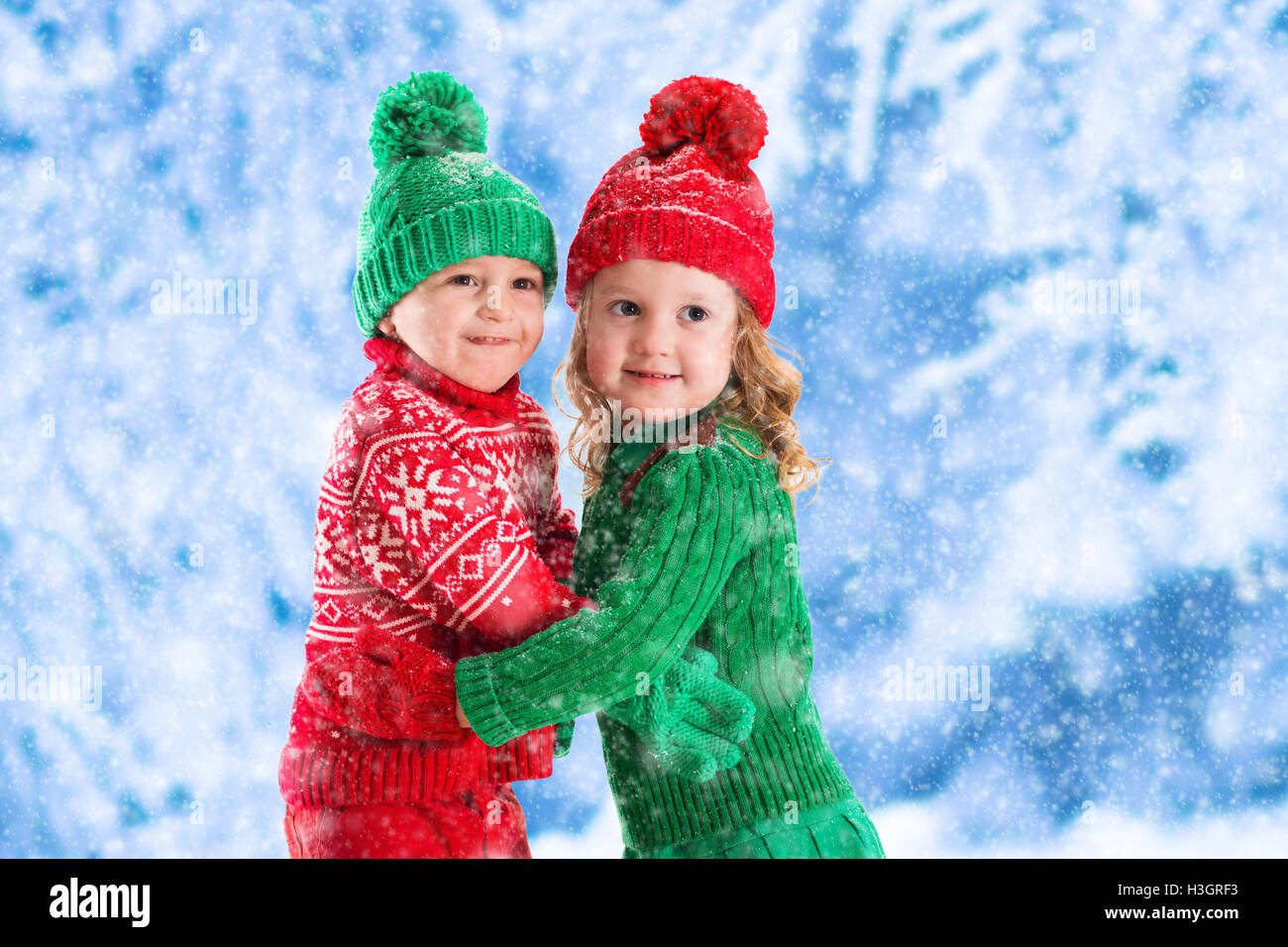 Children play in snowy forest. Toddler kids outdoors in winter. Friends ...