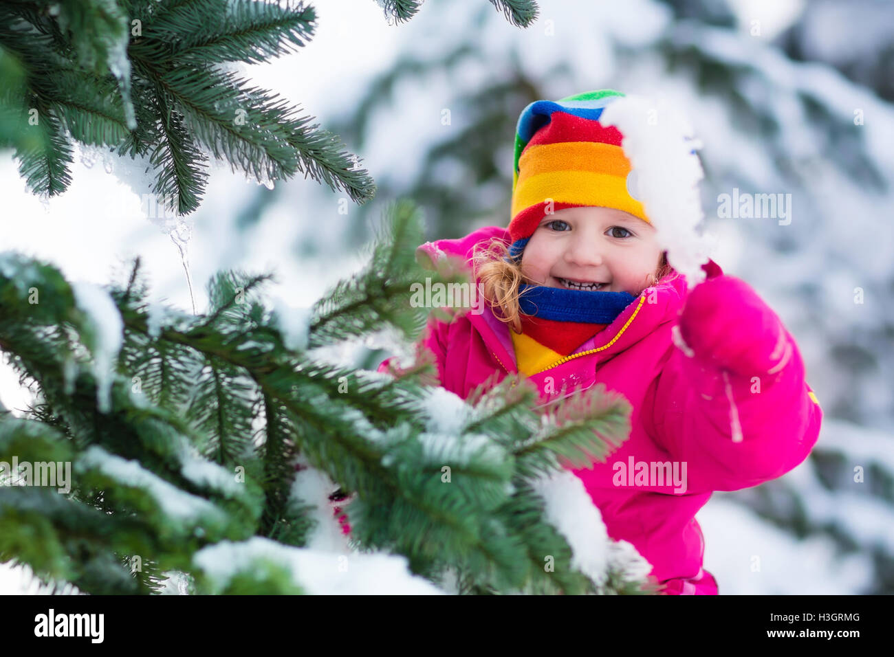 Child playing in snowy forest. Toddler kid holding an icicle outdoors ...