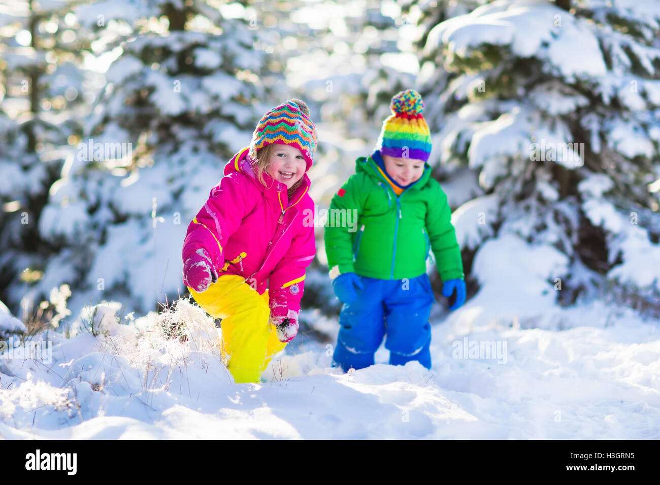 Children play in snowy forest. Toddler kids outdoors in winter. Friends ...