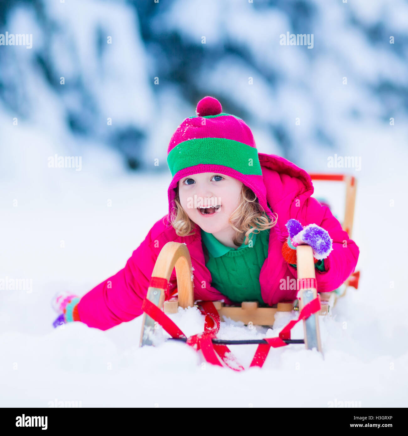 Little girl enjoying a sleigh ride. Child sledding. Toddler kid riding ...