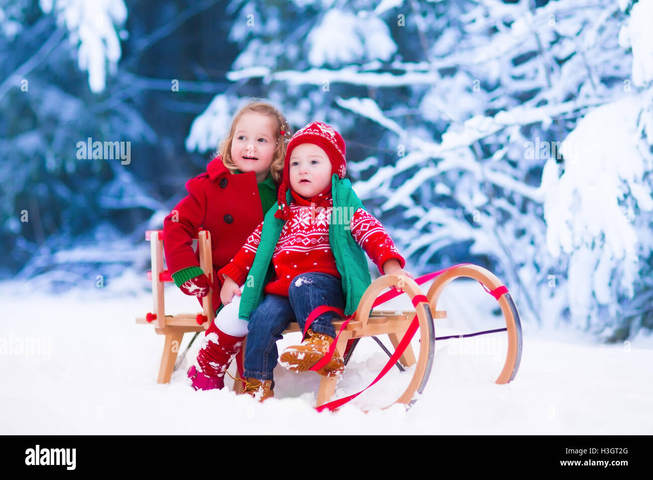 Little girl and boy enjoy a sleigh ride. Child sledding. Toddler kid ...