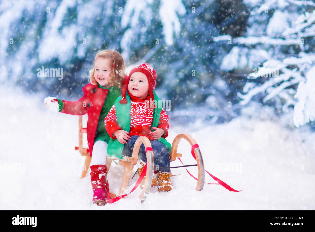 Little girl and boy enjoy a sleigh ride. Child sledding. Toddler kid ...