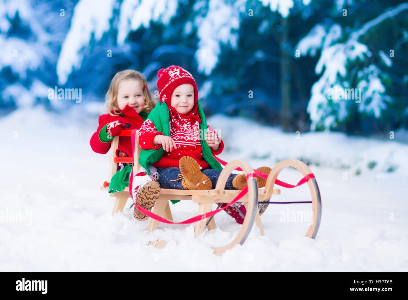 Little girl and boy enjoy a sleigh ride. Child sledding. Toddler kid ...