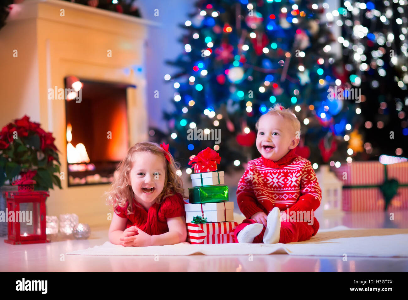 Family on Christmas eve at fireplace. Kids opening Xmas presents ...