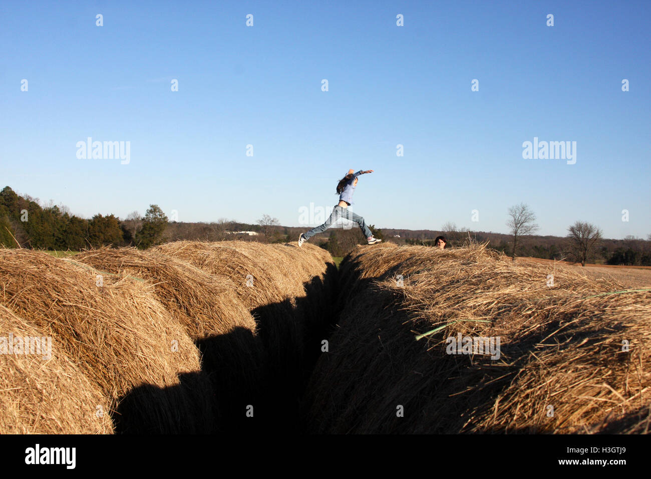 Young girl jumping over hay bales Stock Photo - Alamy