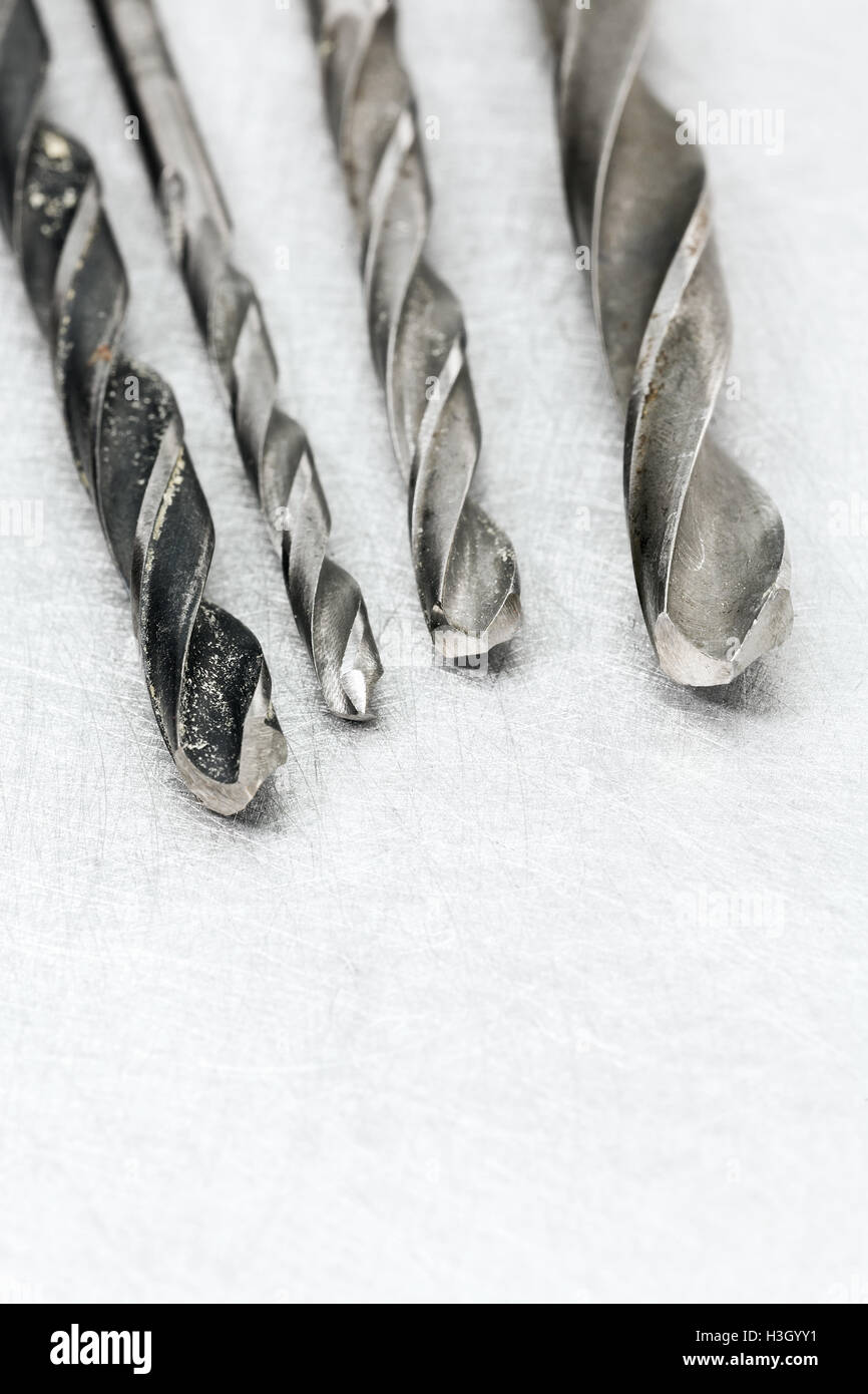 Drill bits closeup view on scratched metal background Stock Photo - Alamy