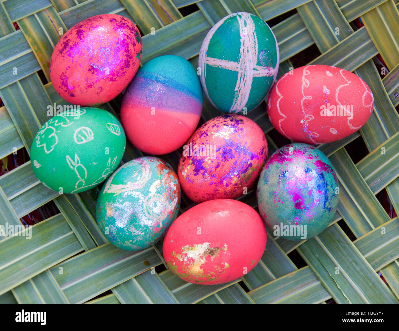 Woven green palm tree leaves with a group of colorfully dyed eggs with ...