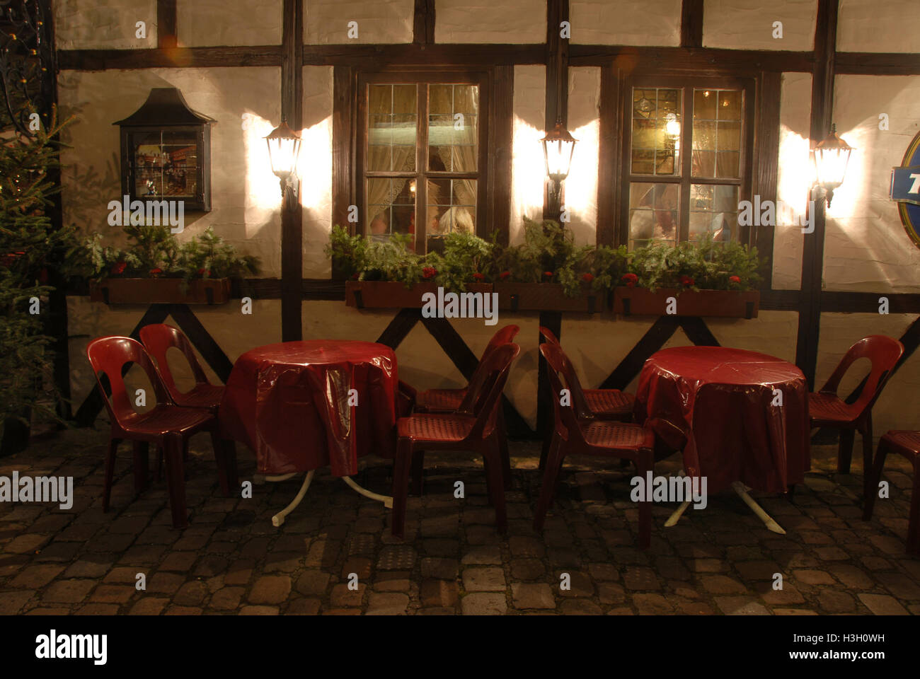 Under dimly-lit lights Empty chairs and tables outside a restaurant in ...