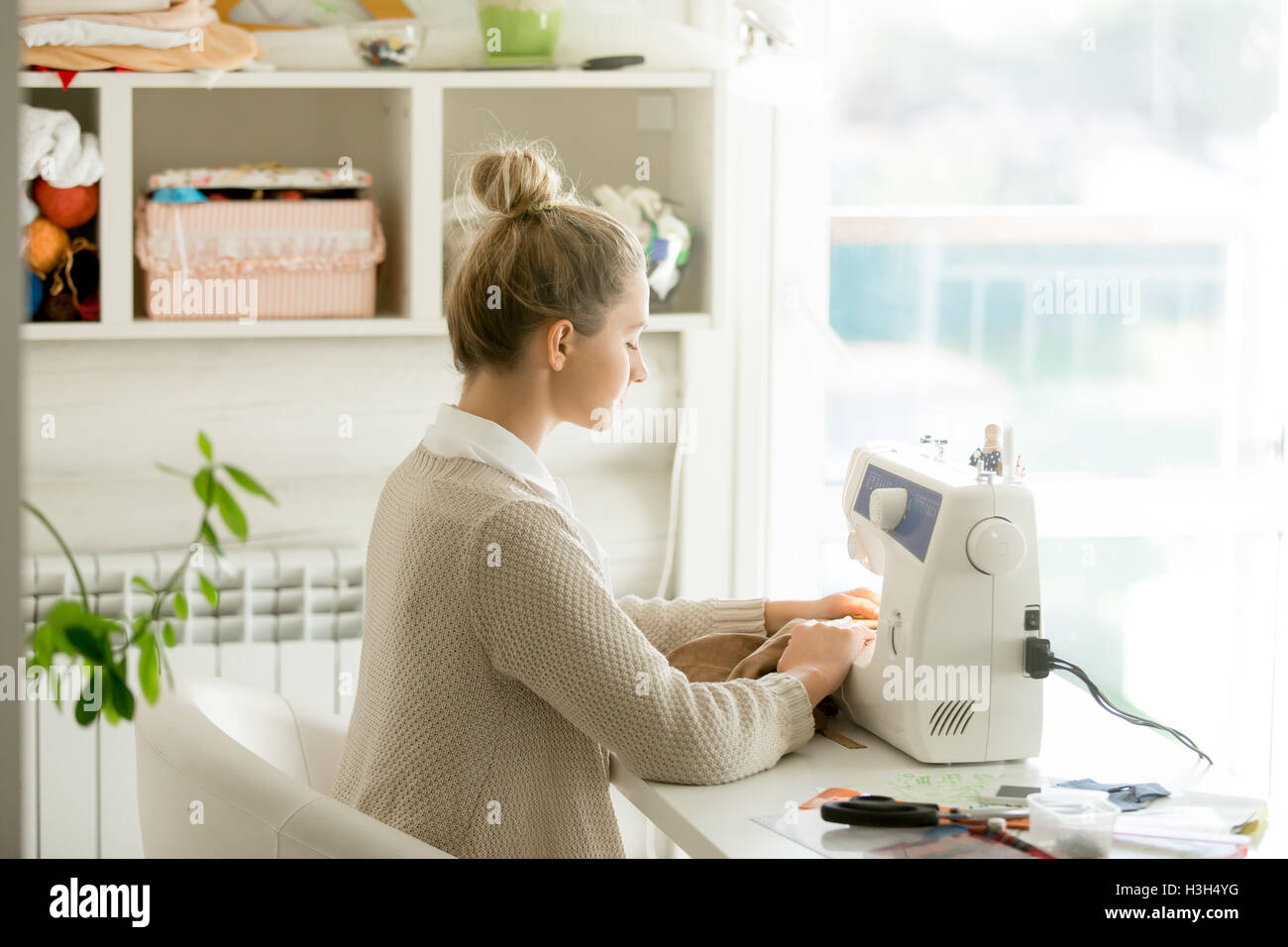 Profile portrait of a young attractive woman at sewing machine Stock ...