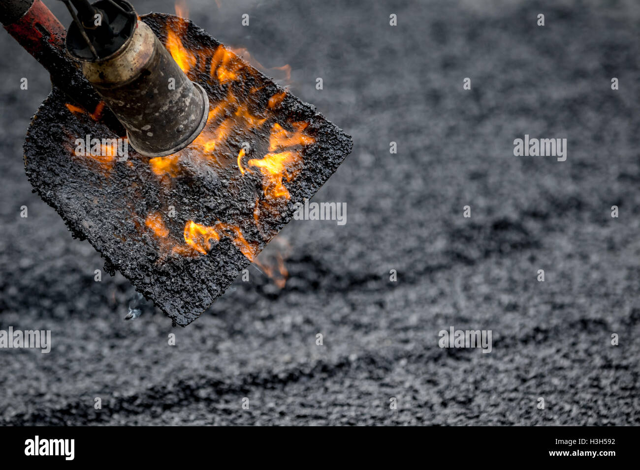 Burning asphalt on a shovel on a brand new road Stock Photo - Alamy