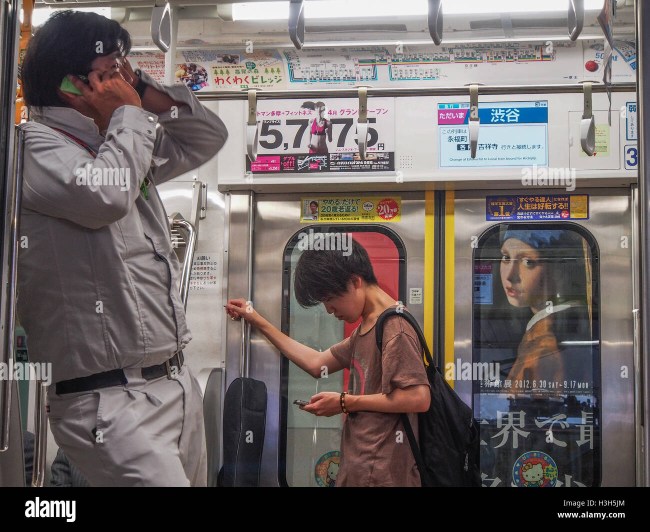 Passengers using phone, on Japanese commuter train, Tokyo. Image of ...