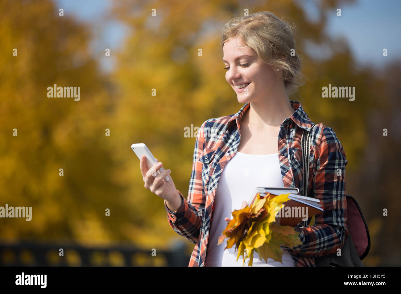 Portrait of student girl outsides, mobile phone in one hand Stock Photo ...