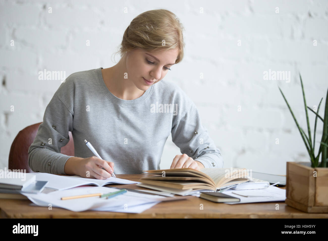 Student female performing a written task in a copybook Stock Photo - Alamy
