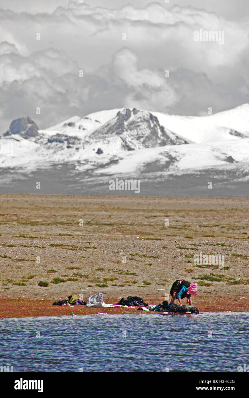 Tibetan lady washes clothes in choppy waters of Lake Namtso in Tibet ...