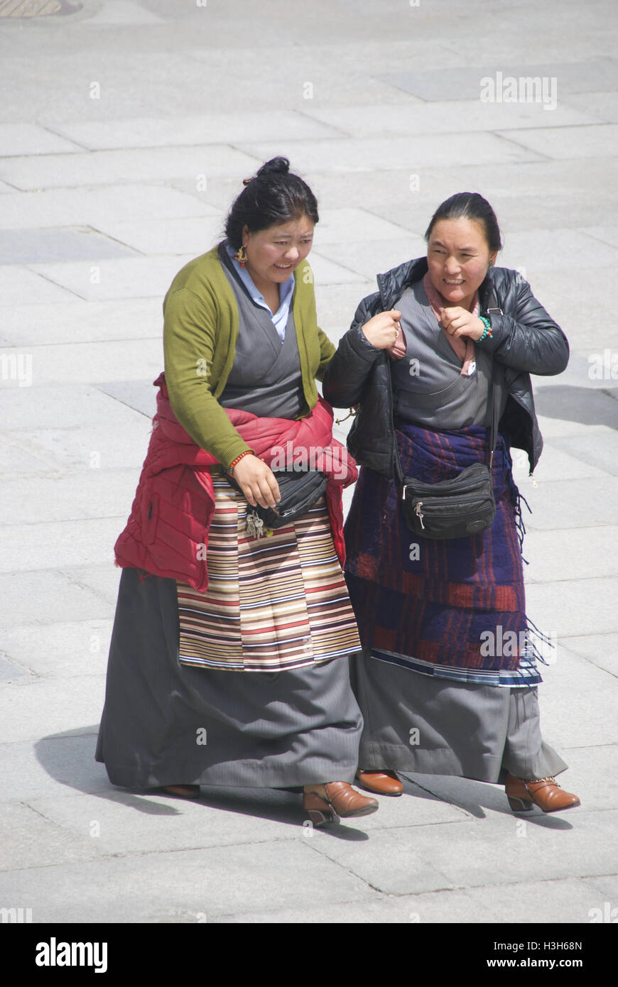 Two Tibetan women stroll down the streets of Lhasa wearing their ...