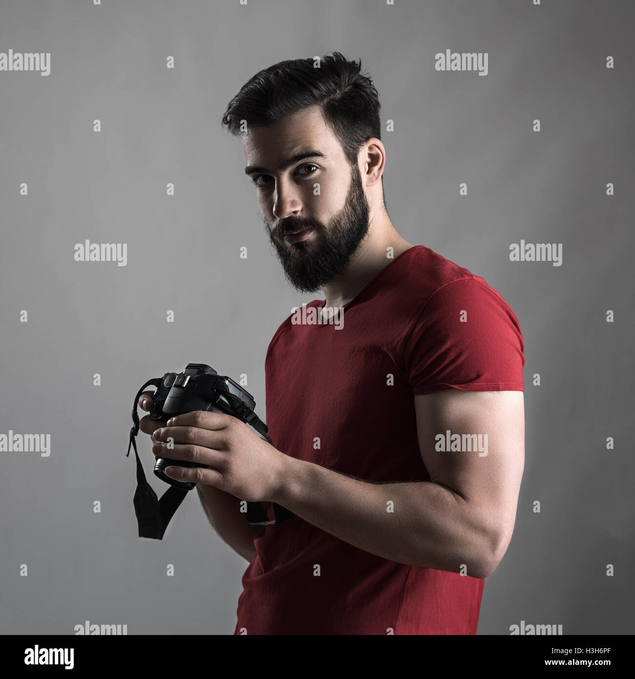 Young bearded photographer artist holding dslr camera. Moody ...