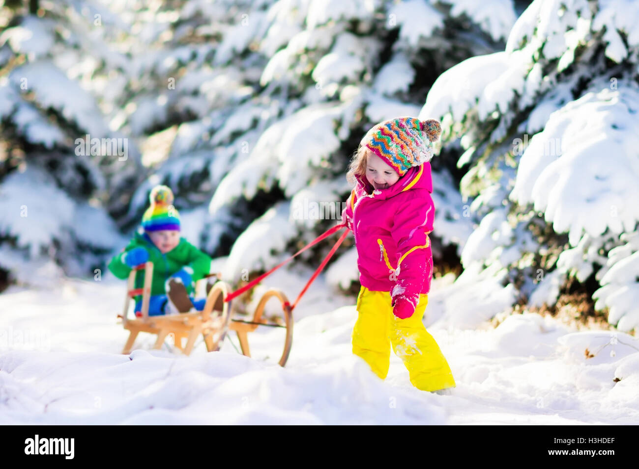 Children play in snowy forest. Toddler kids outdoors in winter. Friends ...
