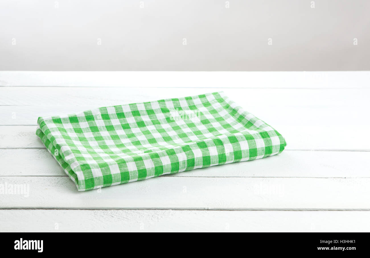 Green folded tablecloth on white table background for product montage ...
