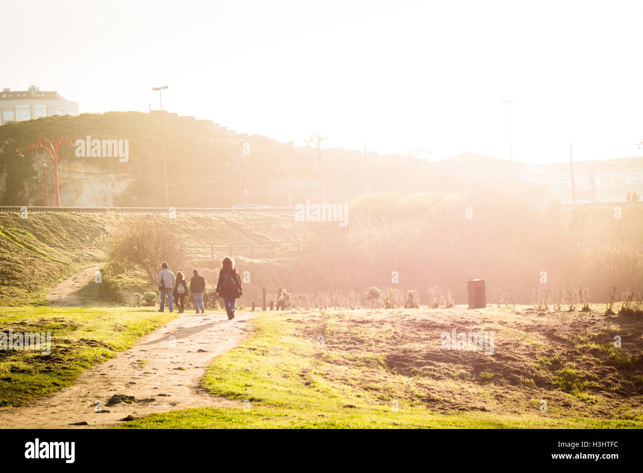 People walking through a park facing the sun Stock Photo - Alamy