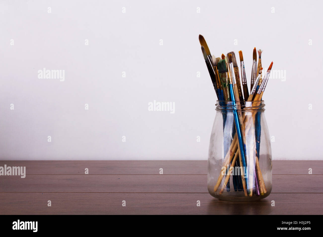 Paint brushes in a glass pot against a white background Stock Photo - Alamy