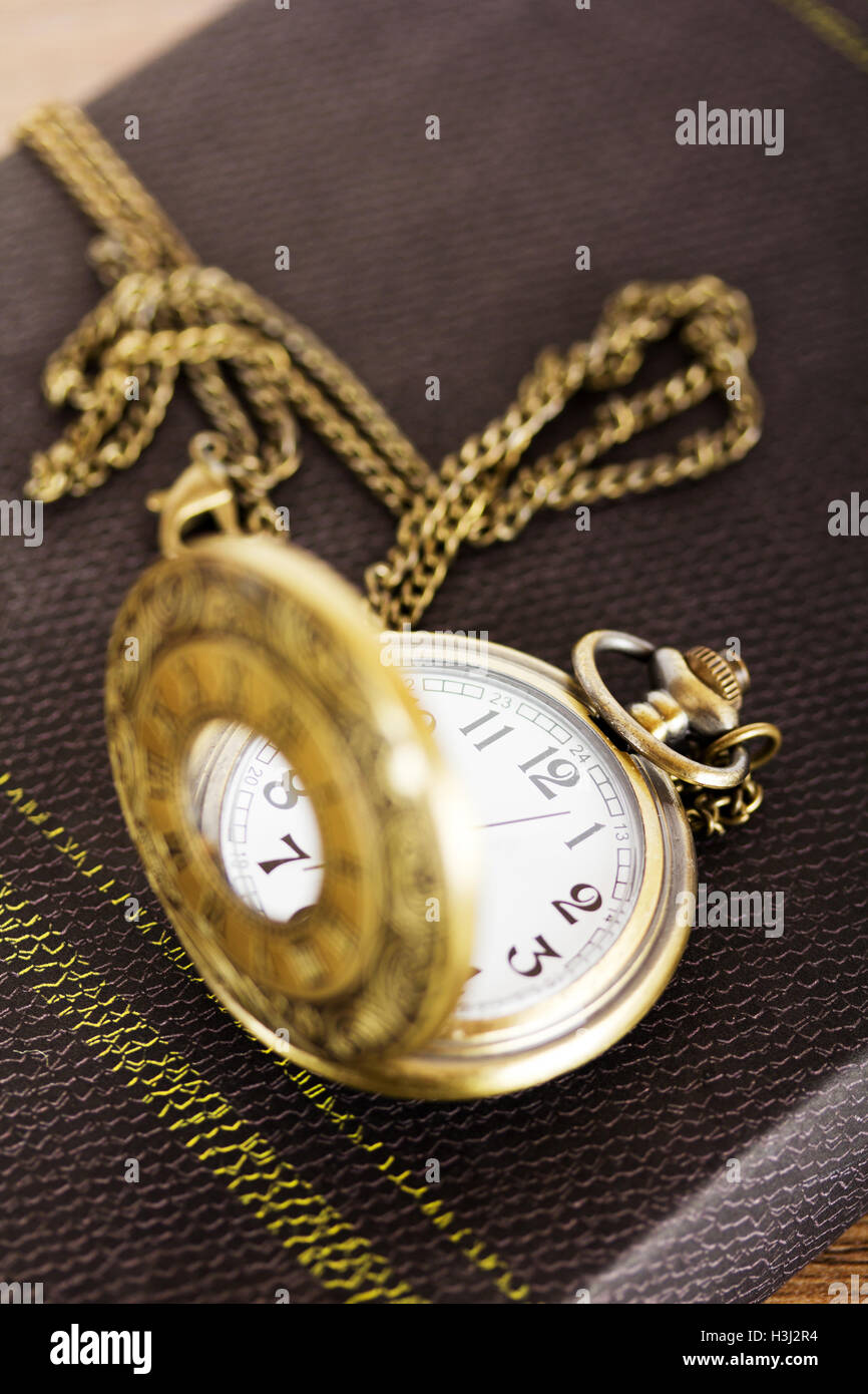 Pocket watch and book against a rustic wooden background Stock Photo ...