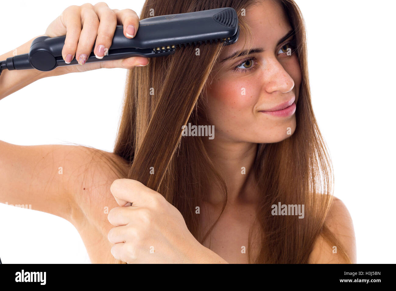 Woman using hair straightener Stock Photo - Alamy