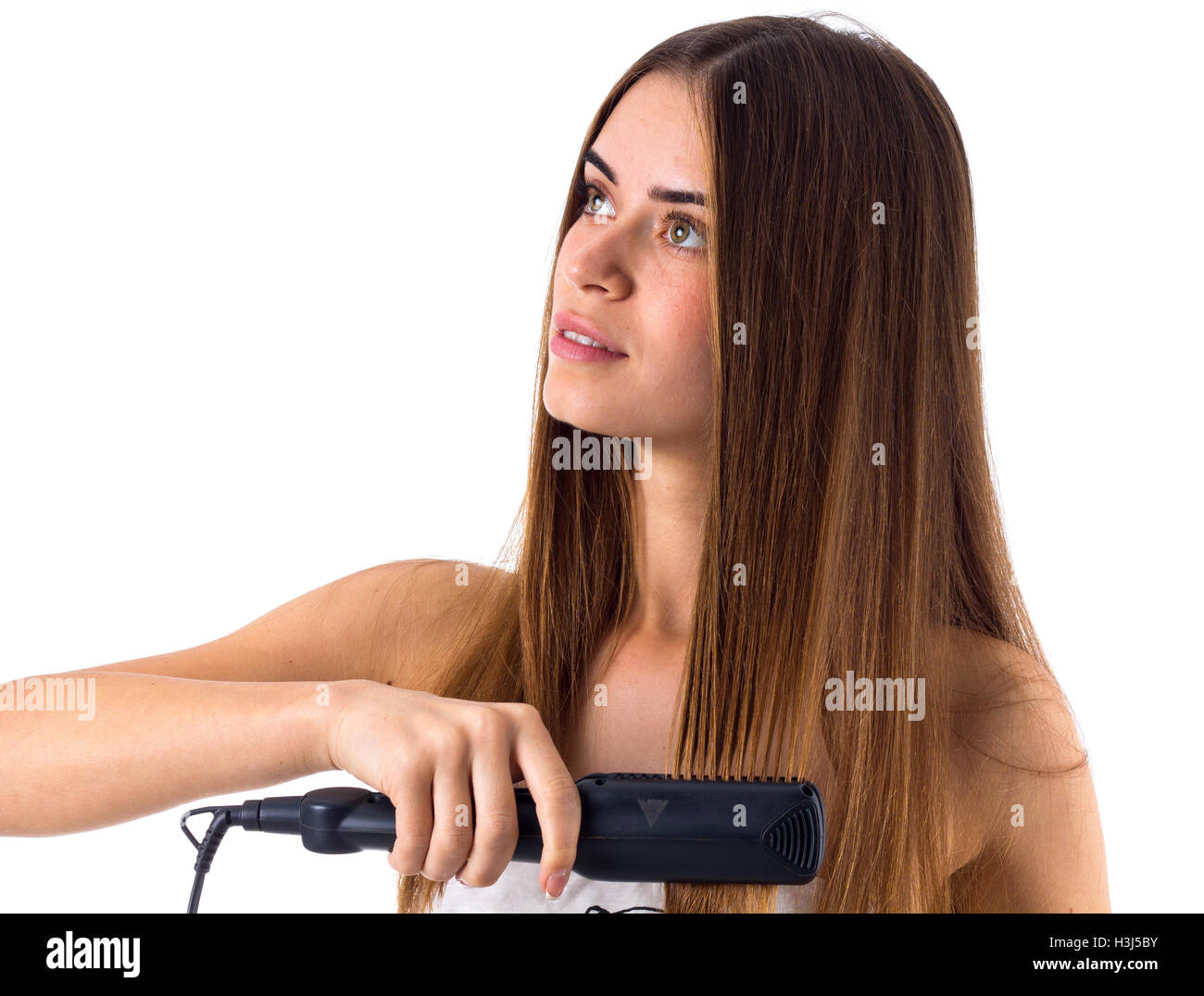 Woman using hair straightener Stock Photo - Alamy