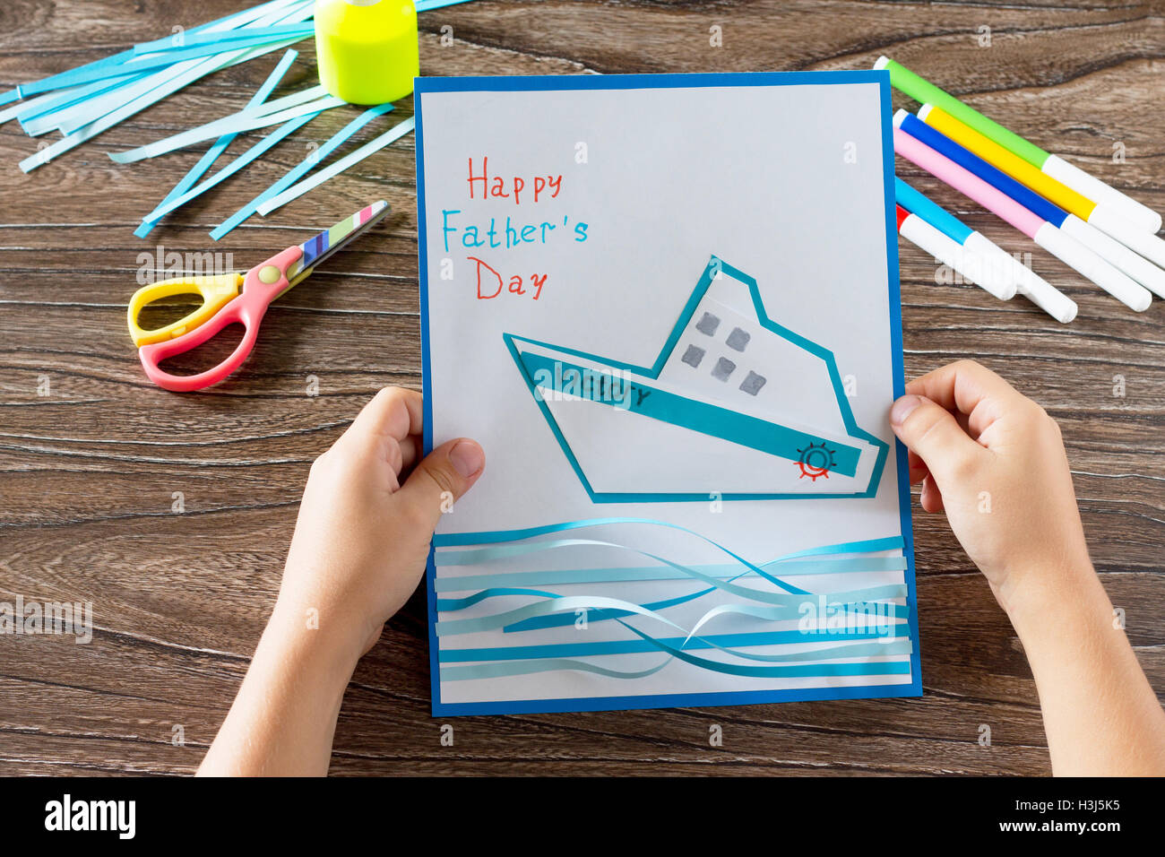 The child makes crafts out of paper boats. Greeting card for on Father ...